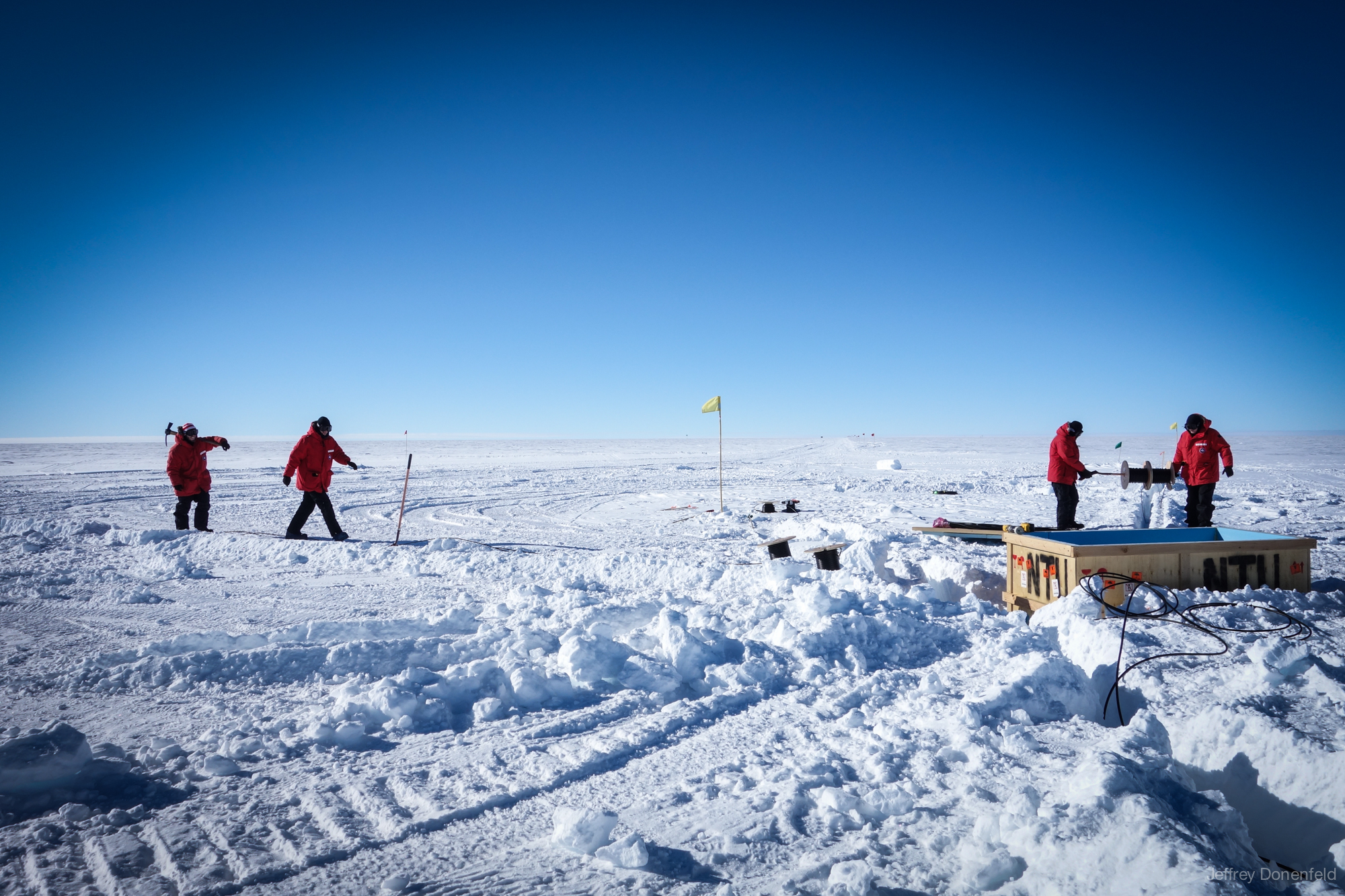 Laying fiberoptic and copper cables into the ice for connecting sensors ...